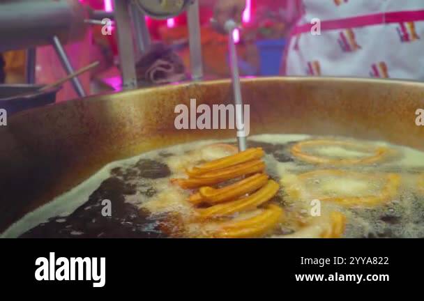 Removes freshly fried churros from the hot oil, observing their golden ...