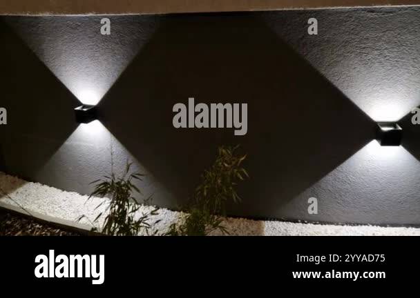 spot wall light illuminates the wall of facade of the house in a ...