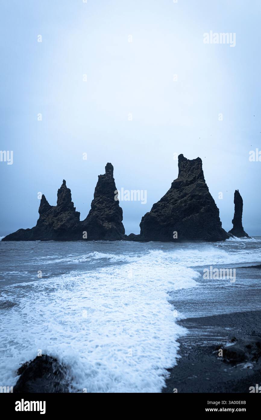 Towering sea stacks stand prominently against a gray sky at a beach ...