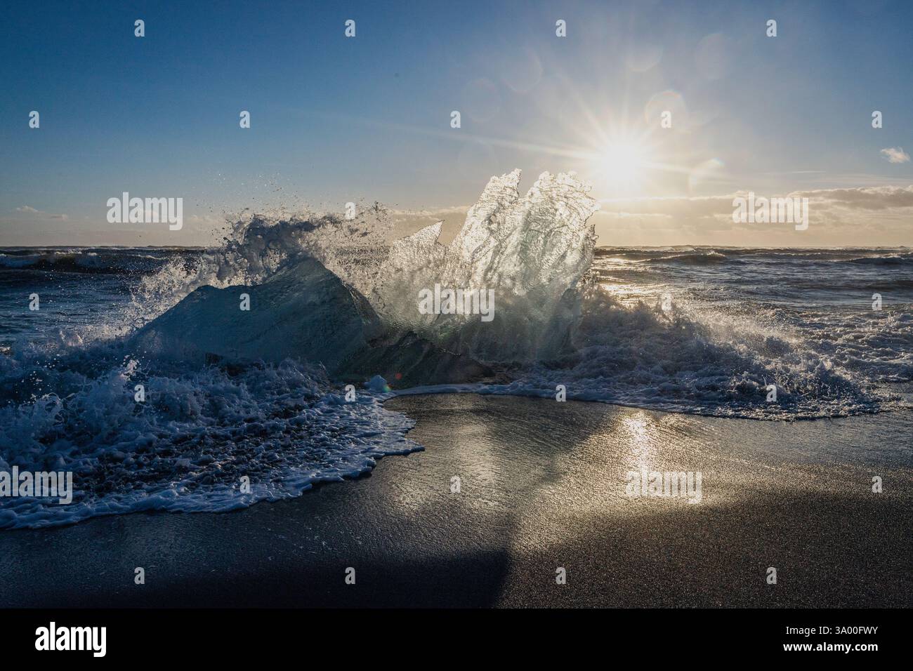 The sun sets on the horizon as waves crash onto the sandy beach ...