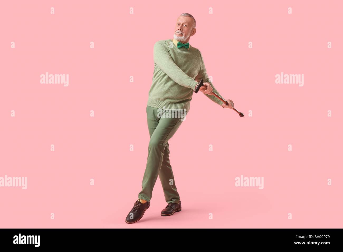 Senior man with walking stick dancing on pink background. National ...