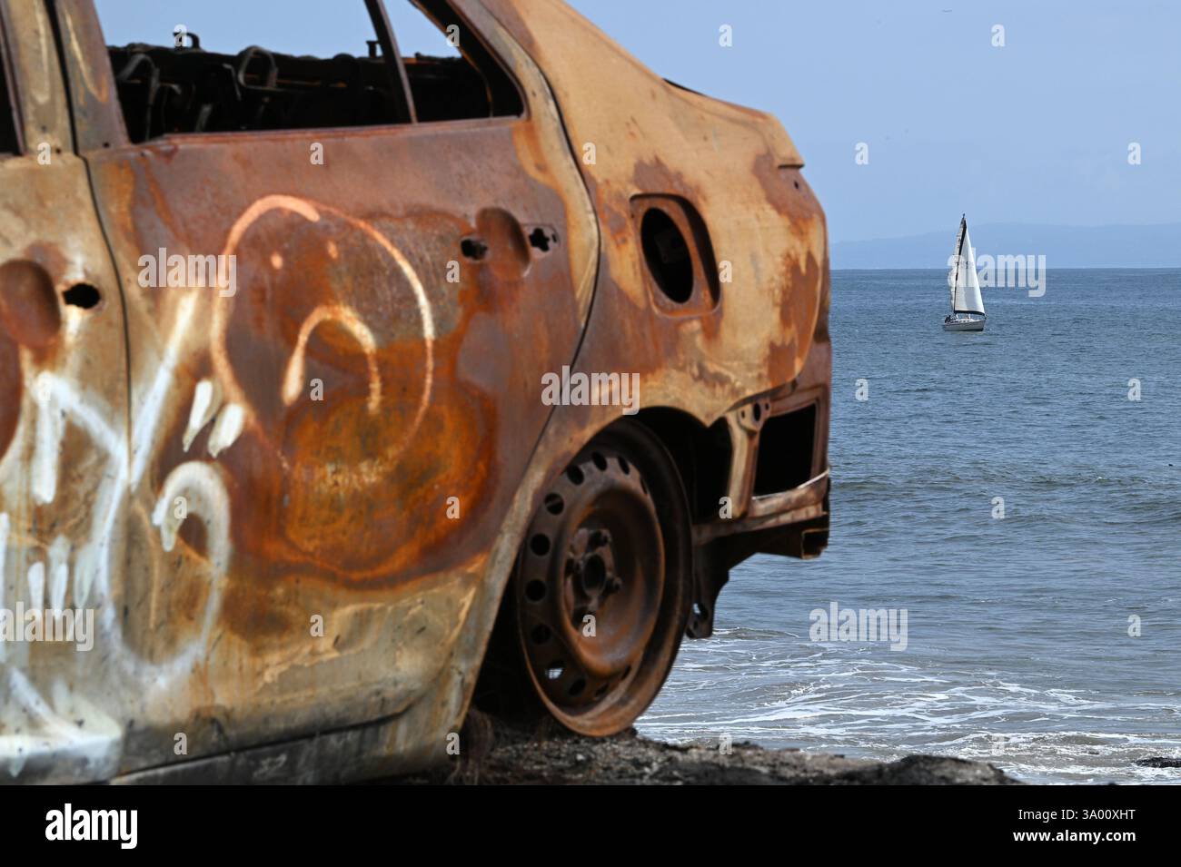 A sailboat seen in the distance passes along Pacific Coast Highway ...