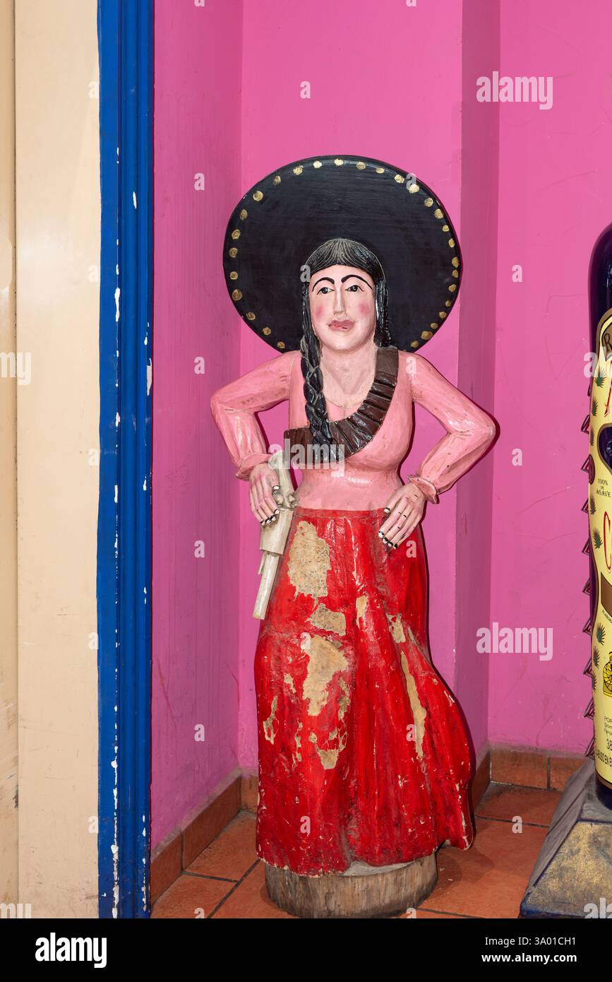 Statue of a female bandit wearing a long red skirt, sombrero and ...