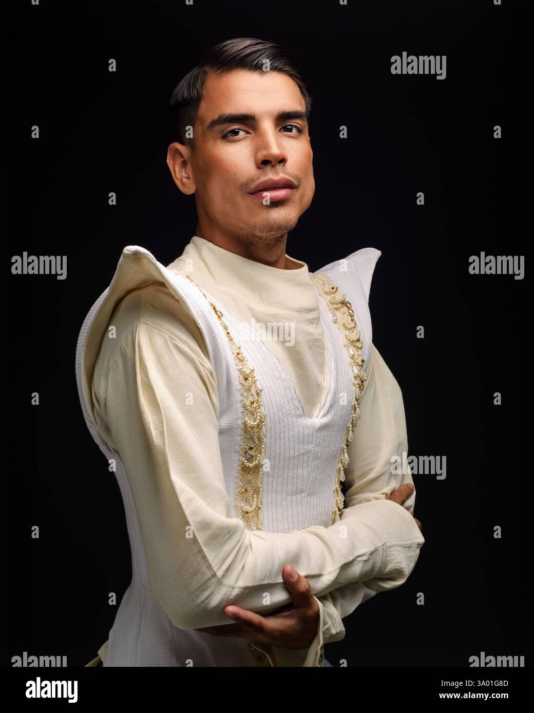 A confident man, likely a model or actor, poses in a studio setting ...