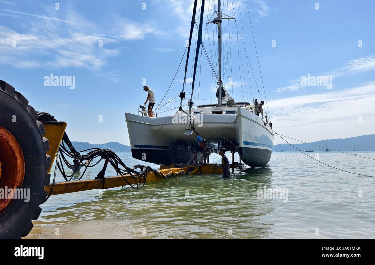 Yellow tractor is pulling a boat out of the water in a beautiful ...