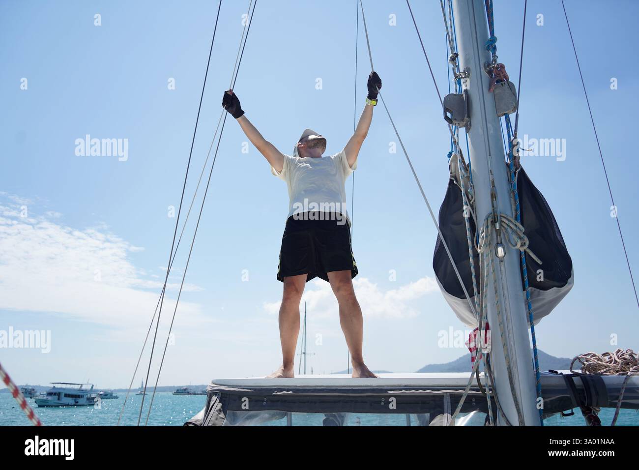 Male captain on deck of sailboat opening sails pulling the rope Stock ...
