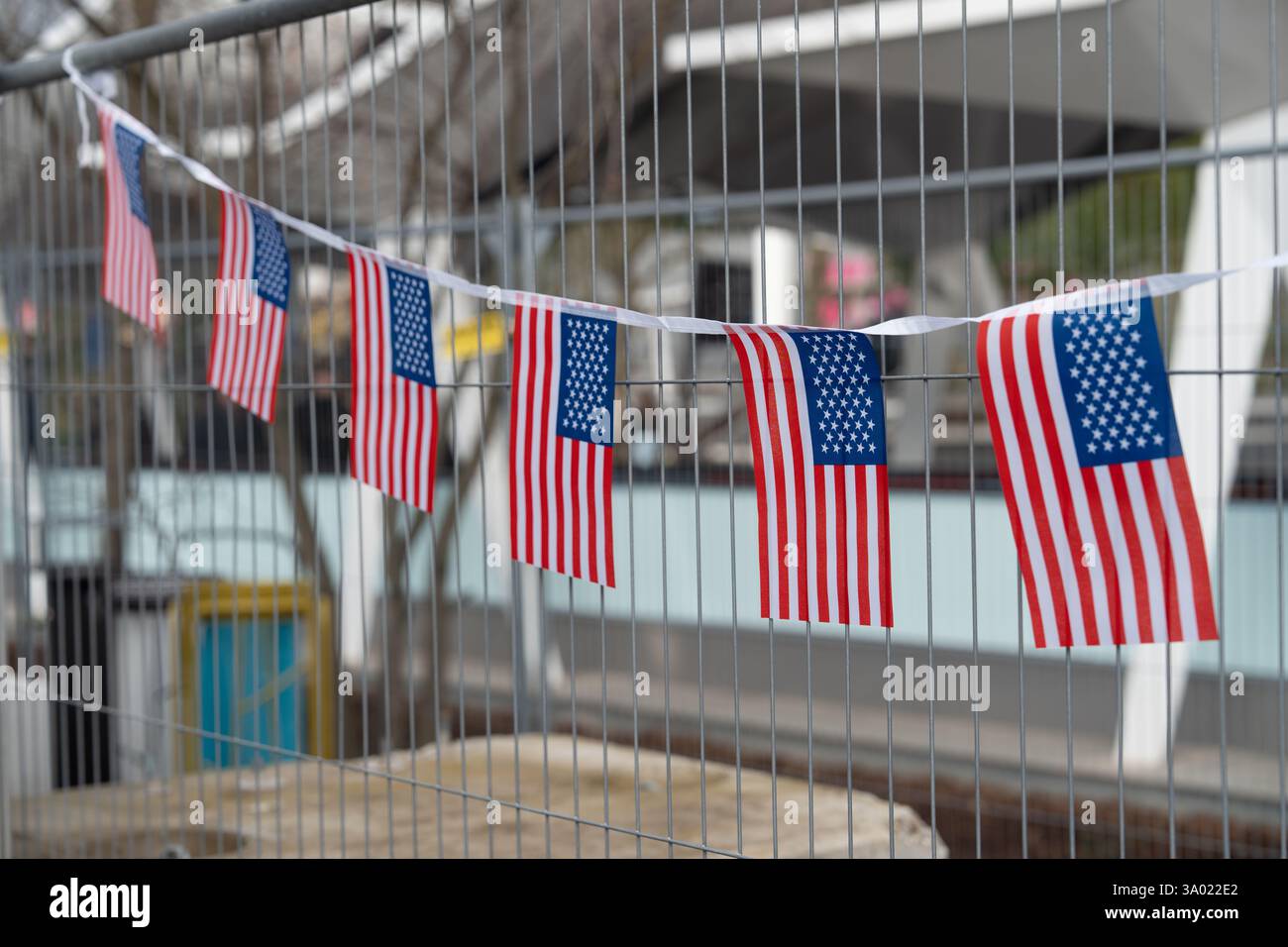 American flags line a fence at a community event by the waterfront ...