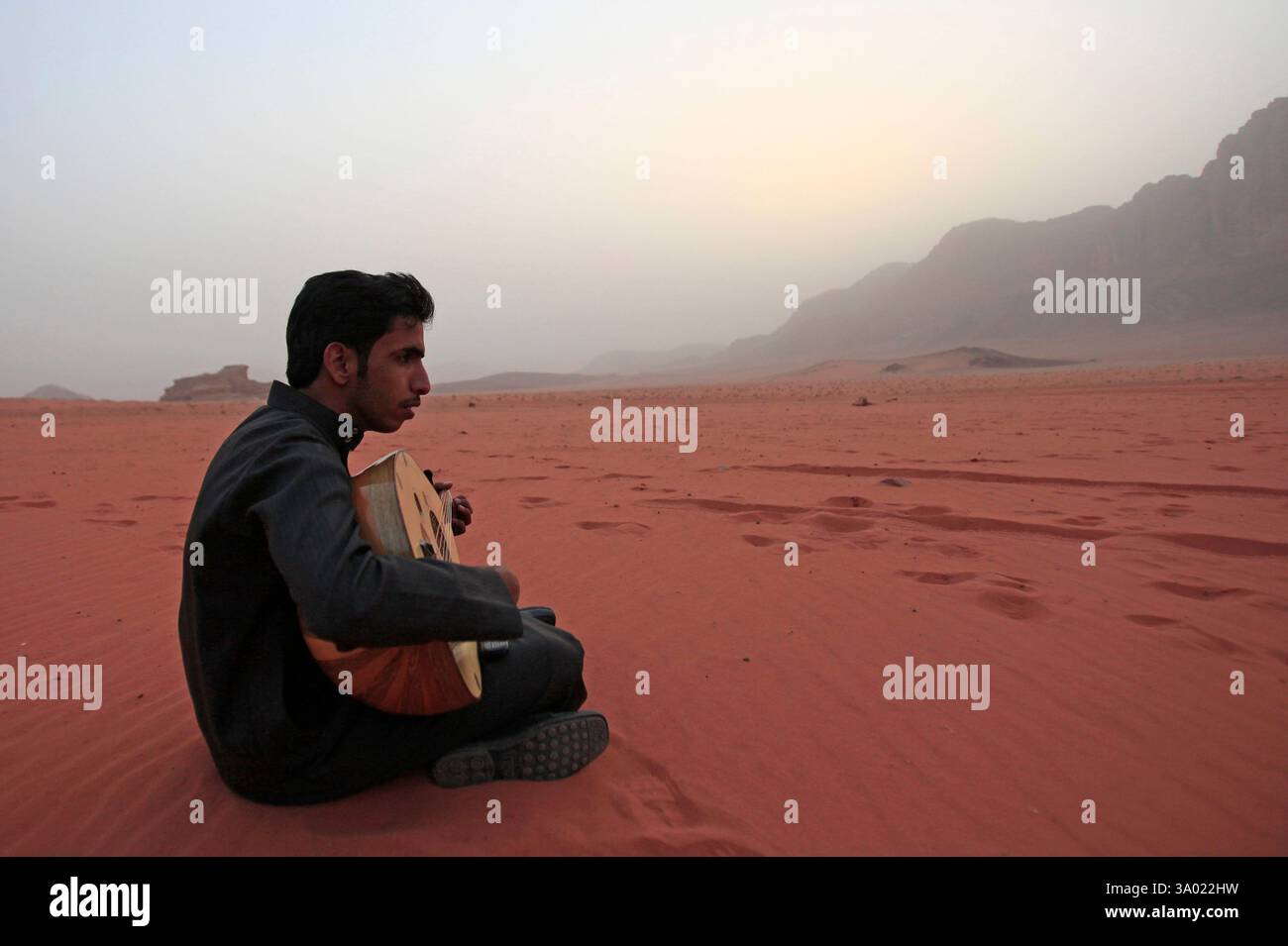 A young Bedouin man plays the Ud string guitar in the desert of Wadi ...
