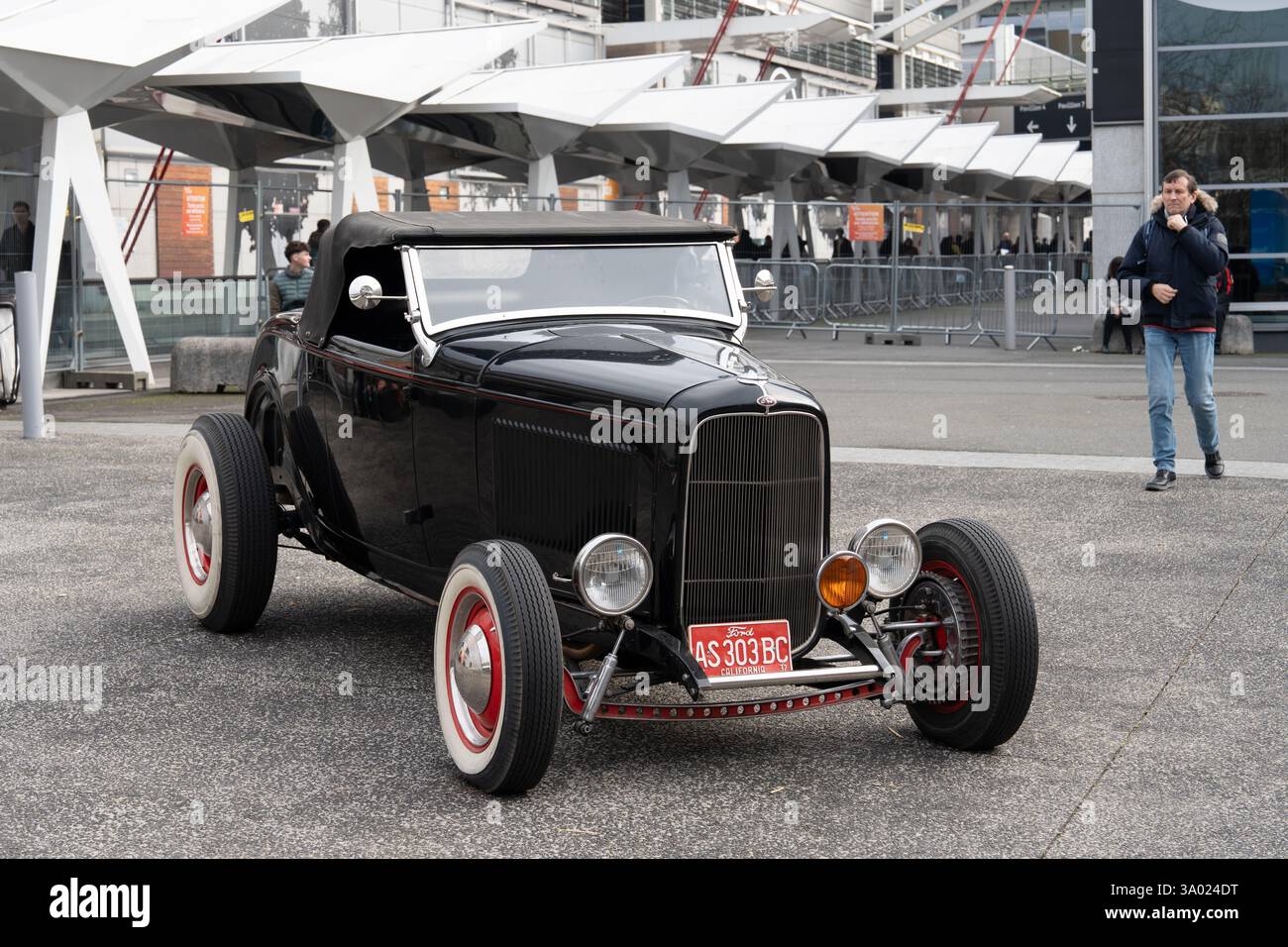Classic hot rod cruises through urban landscape at a vibrant car show ...