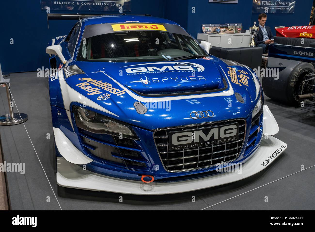 Racing enthusiasts admire a vibrant blue sports car at an auto show in ...