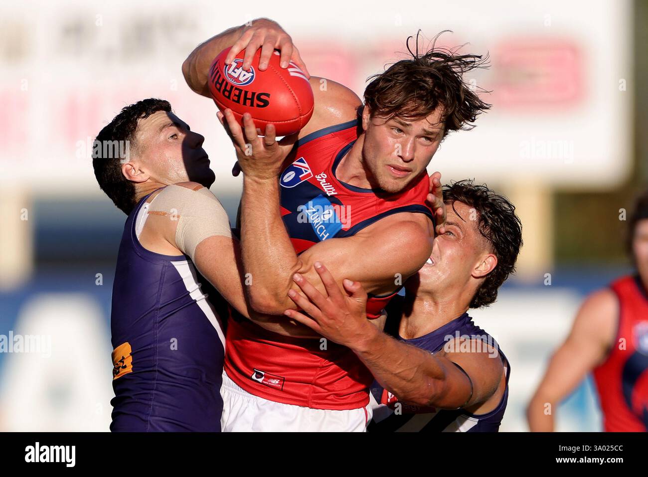 Blake Howes of the Demons is tackled during the AFL Community Series ...