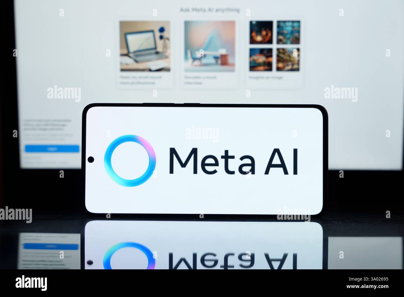 Smartphone displays Meta AI logo. Computer screen in background shows ...