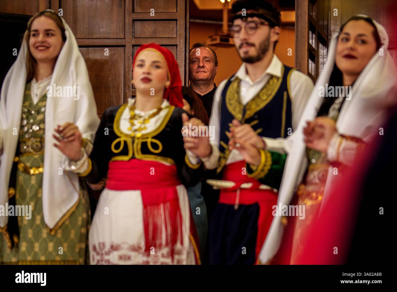 A man watches members of a Romanian ethnic Greek group dancing during a ...