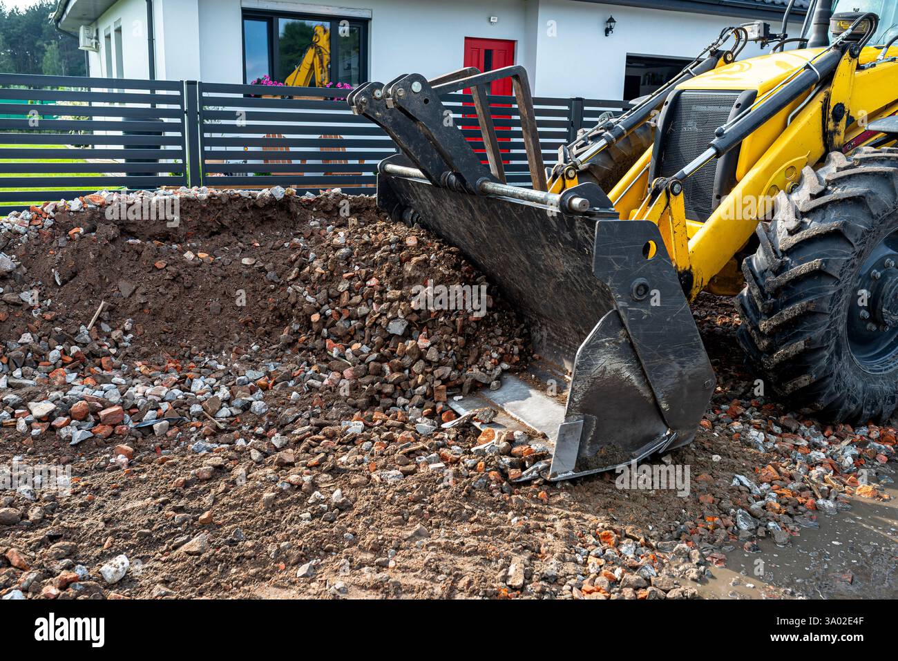 A backhoe loader carries and levels rubble on a dirt road Stock Photo ...