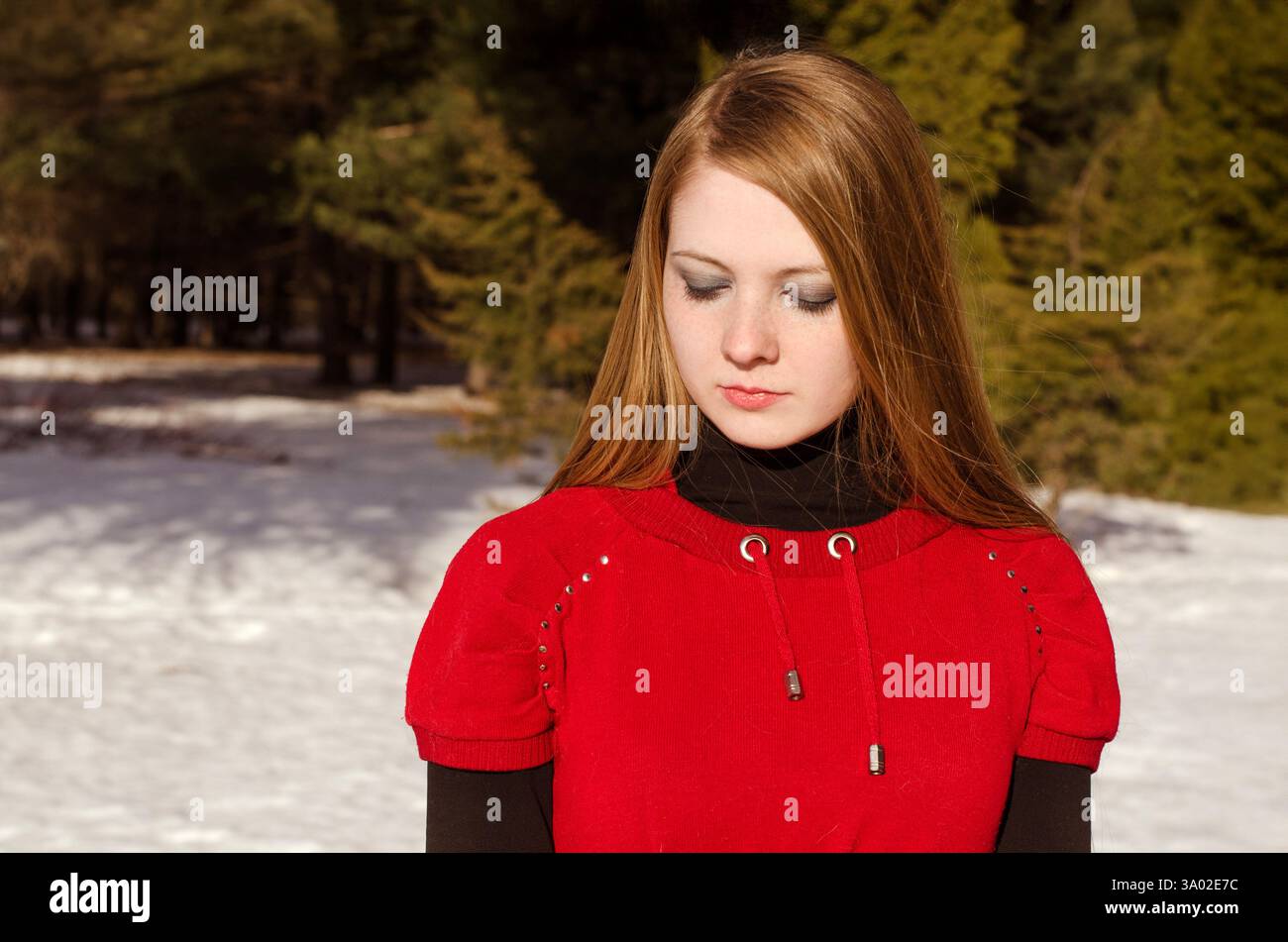 Young woman with red hair and pale skin stands in snowy forest. Wearing ...