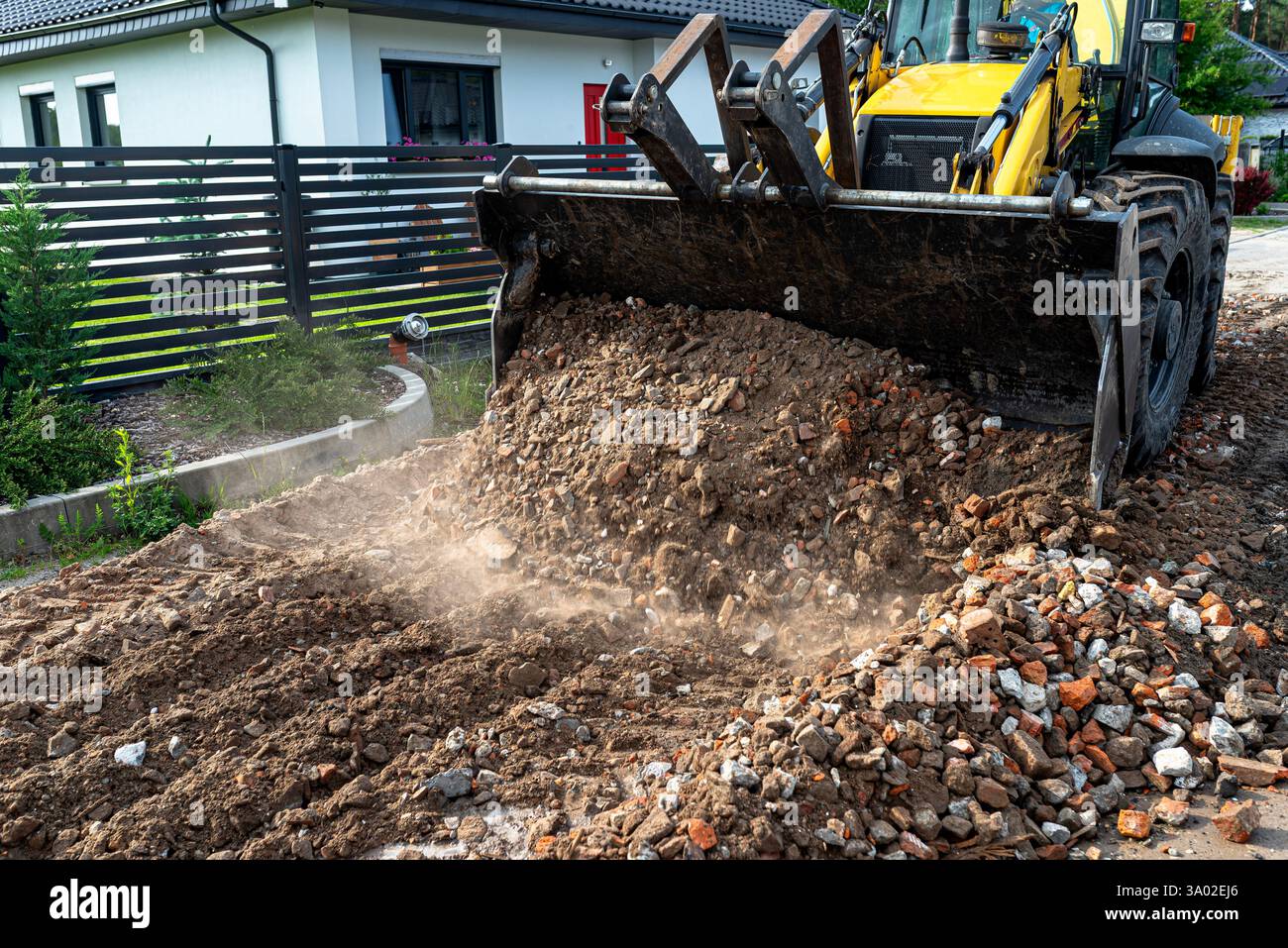 A backhoe loader carries and levels rubble on a dirt road Stock Photo ...