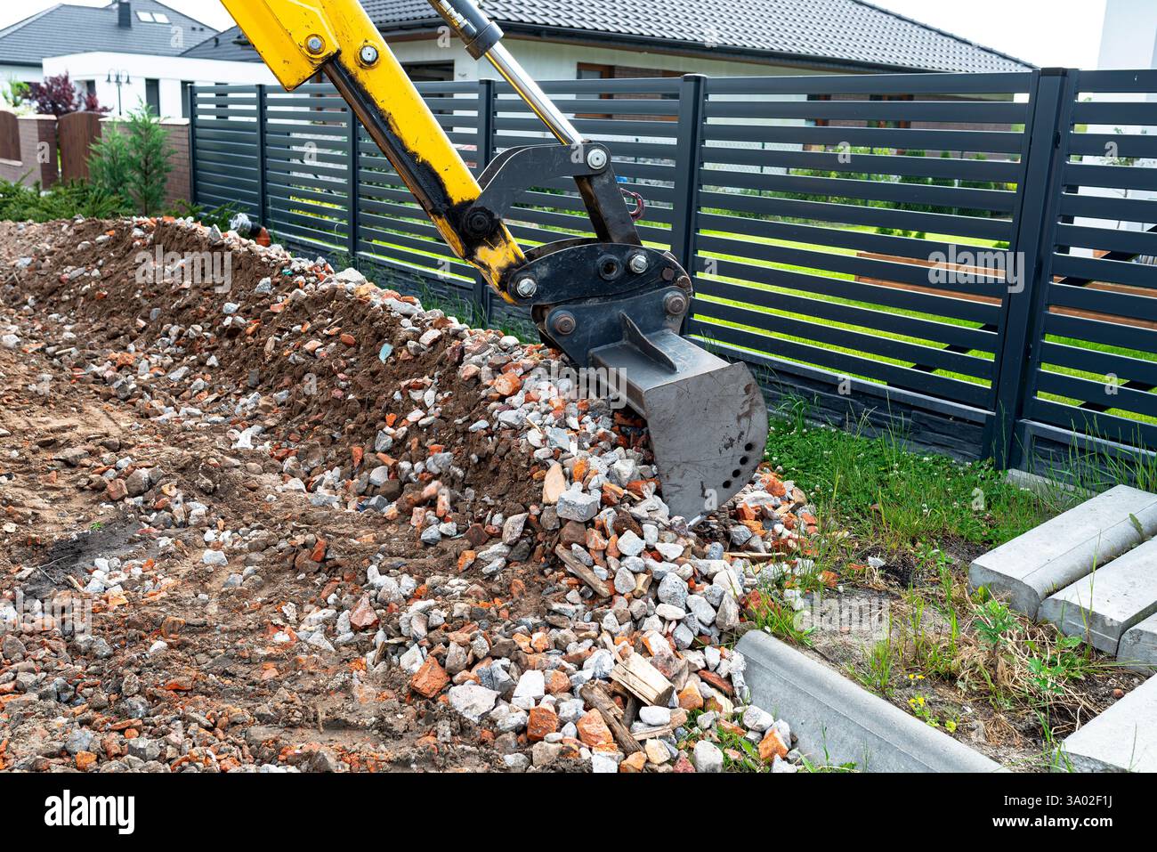 A backhoe loader picks up rubble with a telescopic bucket to level the ...
