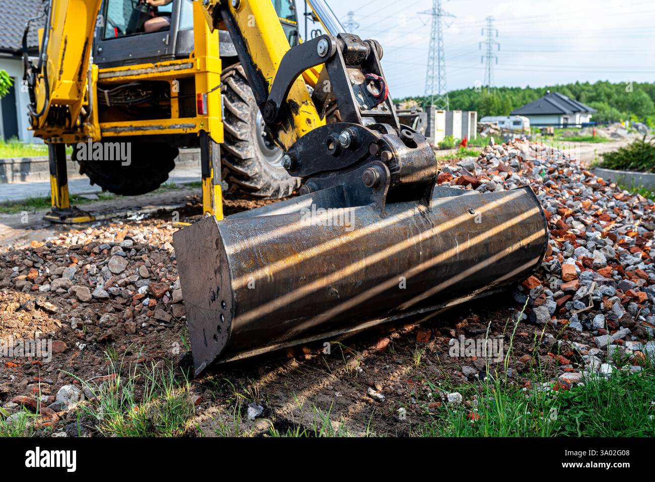 A backhoe loader picks up rubble with a telescopic bucket to level the ...