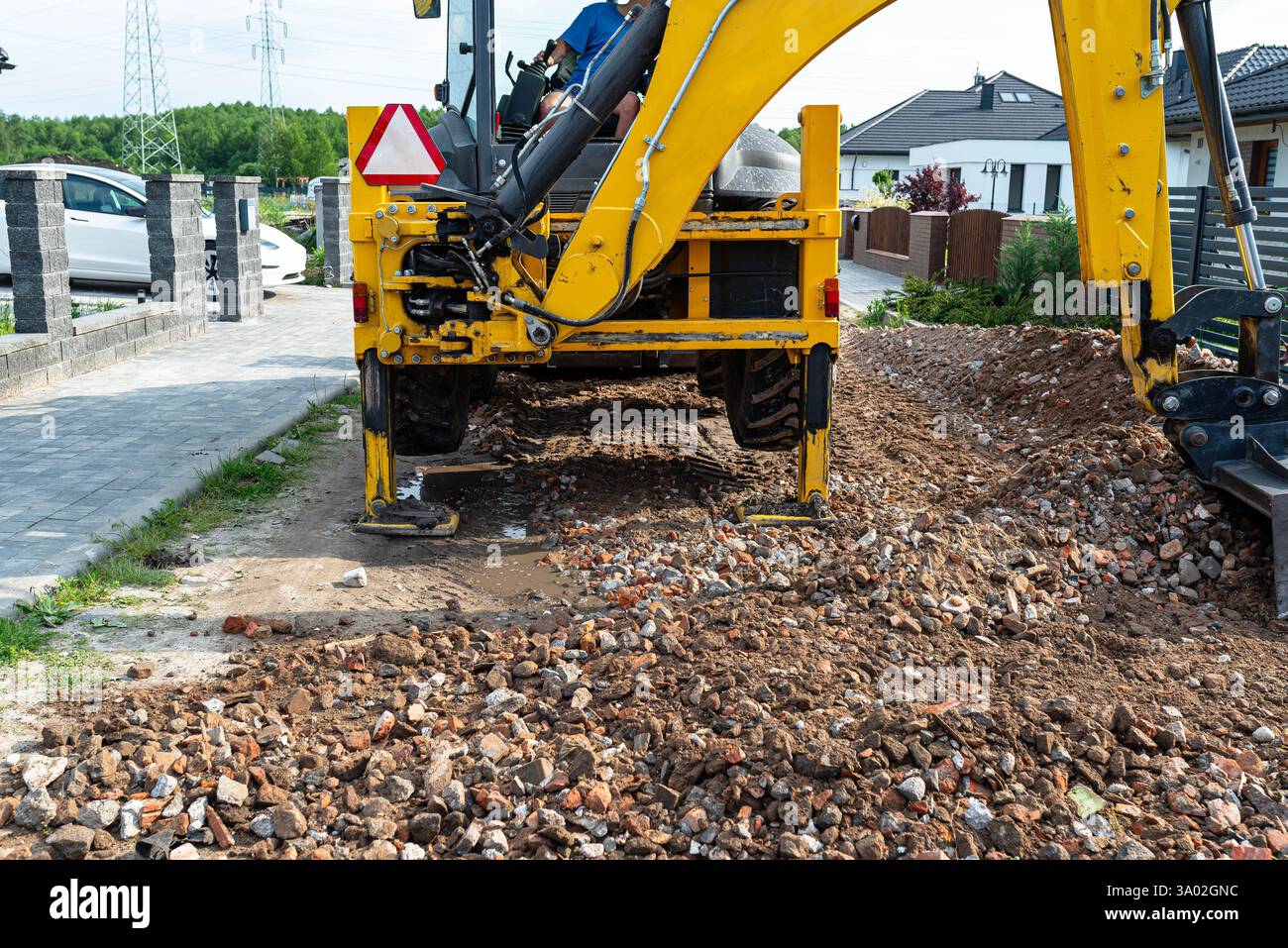 A backhoe loader raised on hydraulic cylinders lifts rubble with a ...