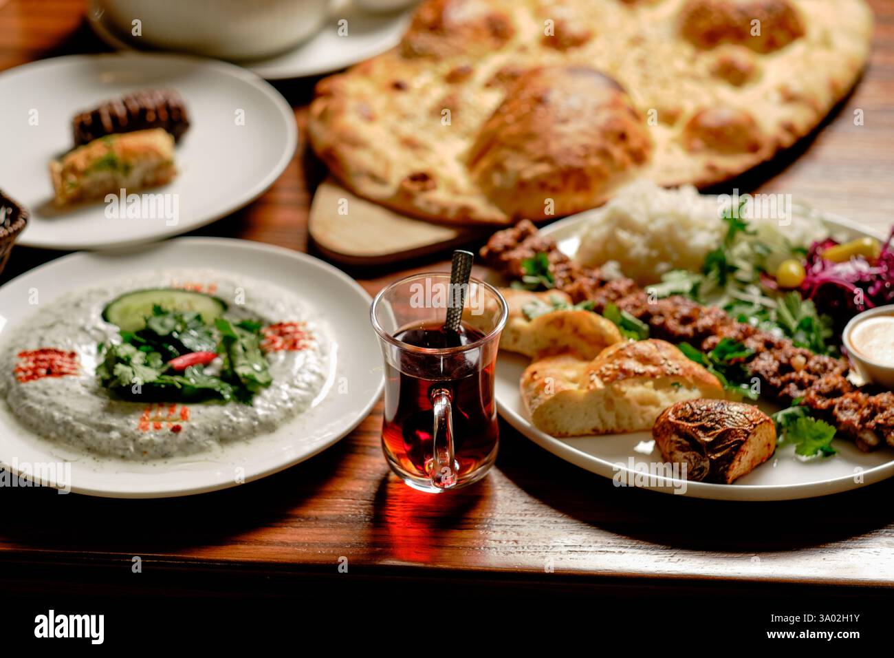 A glass of Turkish tea with various Turkish dishes on the table ...