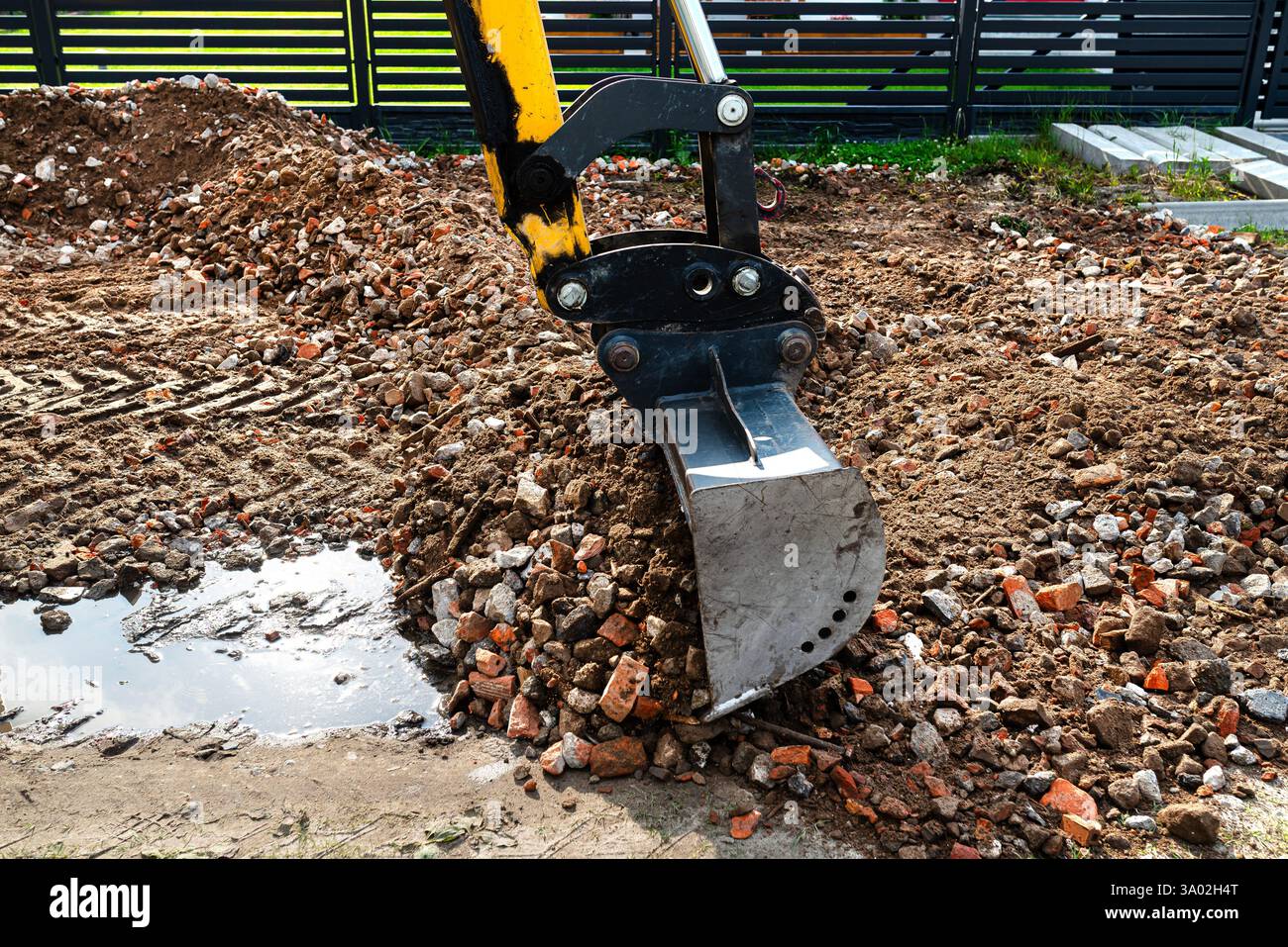A backhoe loader picks up rubble with a telescopic bucket to level the ...