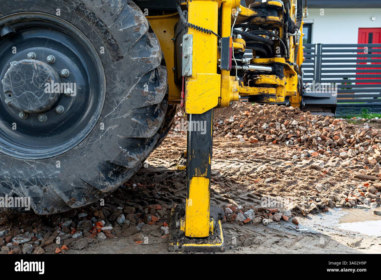 A backhoe loader raised on hydraulic cylinders lifts rubble with a ...