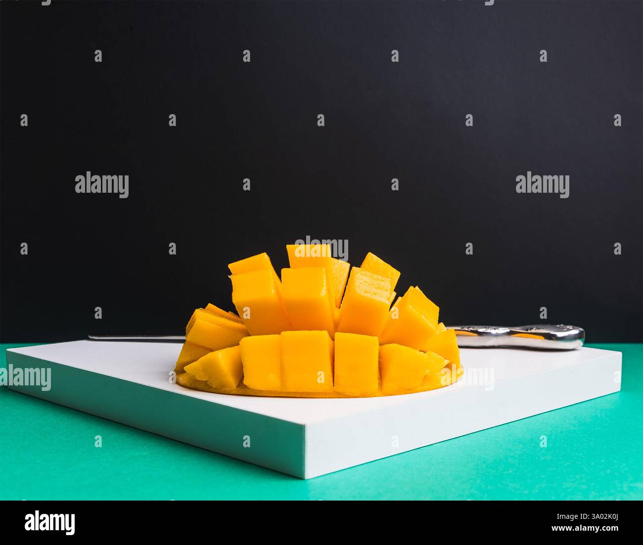 Bright yellow mango cubes are neatly cut and displayed on a clean white ...