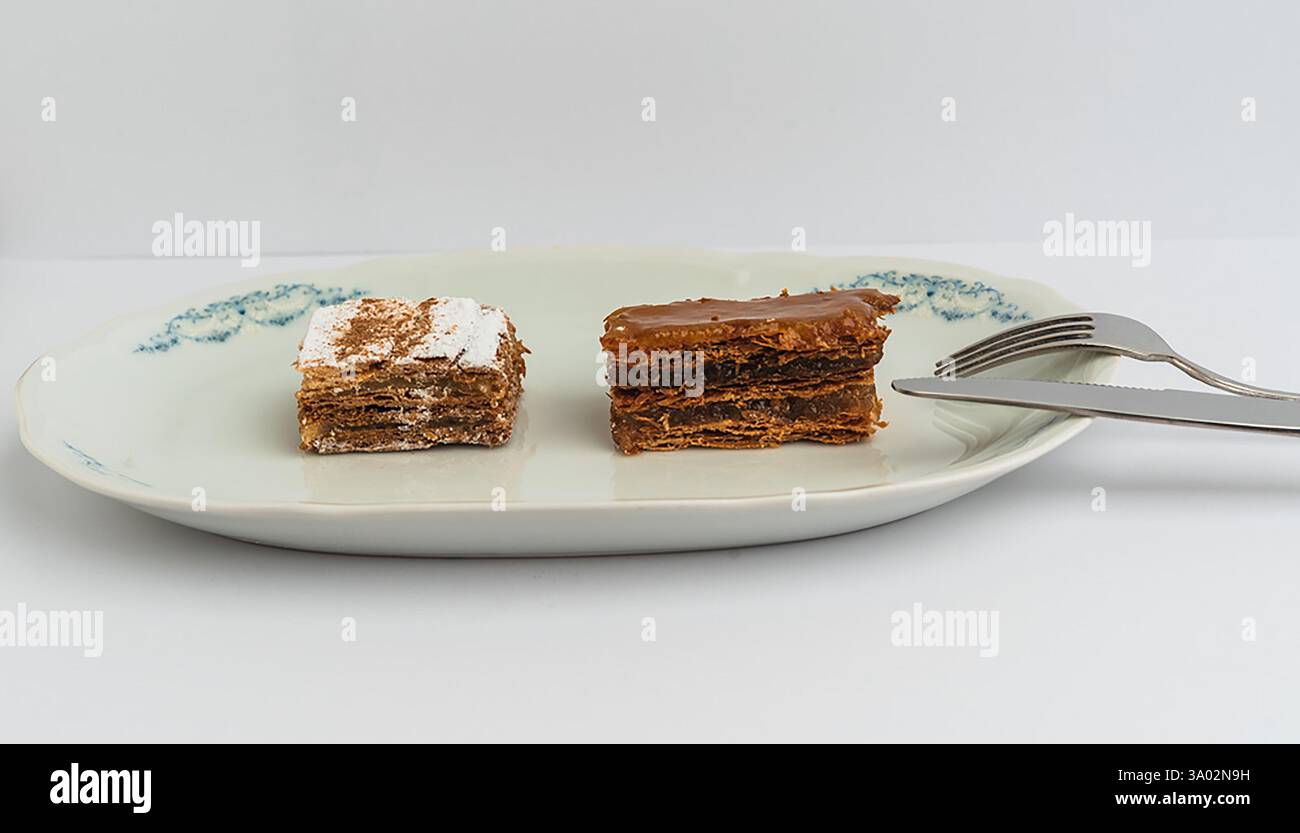 Two distinct layered pastries sit on an elegant plate, showcasing ...