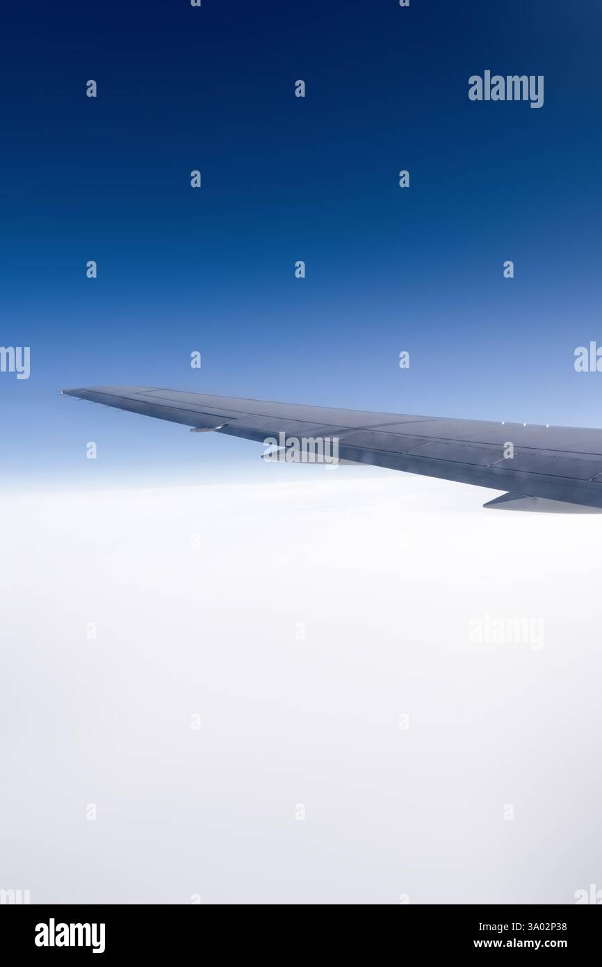 A breathtakingly stunning view of an airplane wing gracefully soaring high above fluffy clouds ...