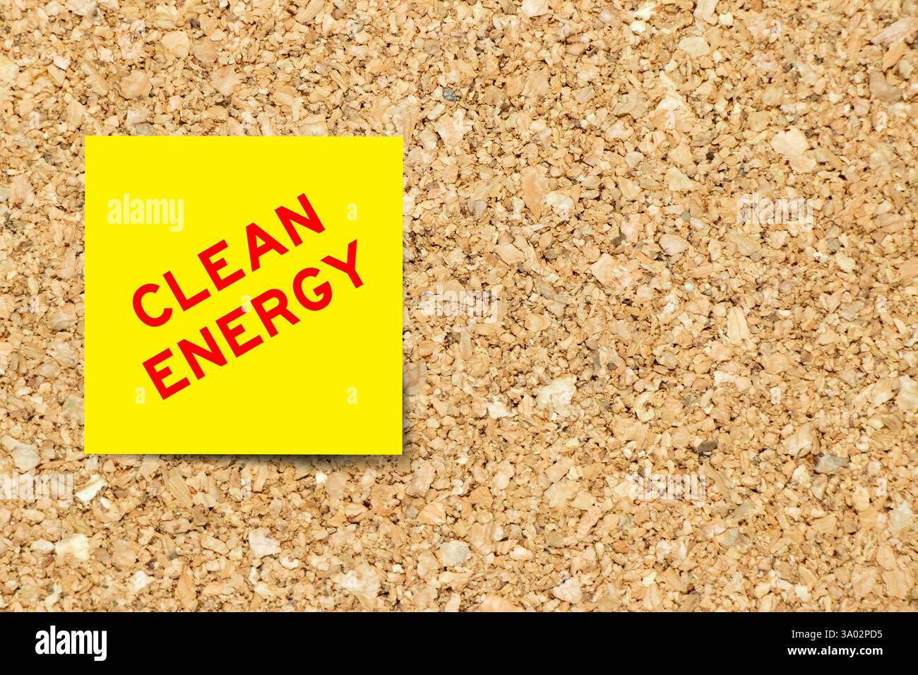 Yellow note paper with word clean energy on cork board background with ...
