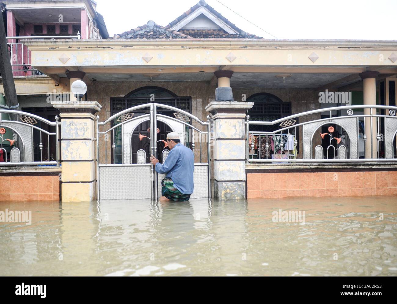 (250302) -- GRESIK, March 2, 2025 (Xinhua) -- A man walks through flood water after heavy rain ...