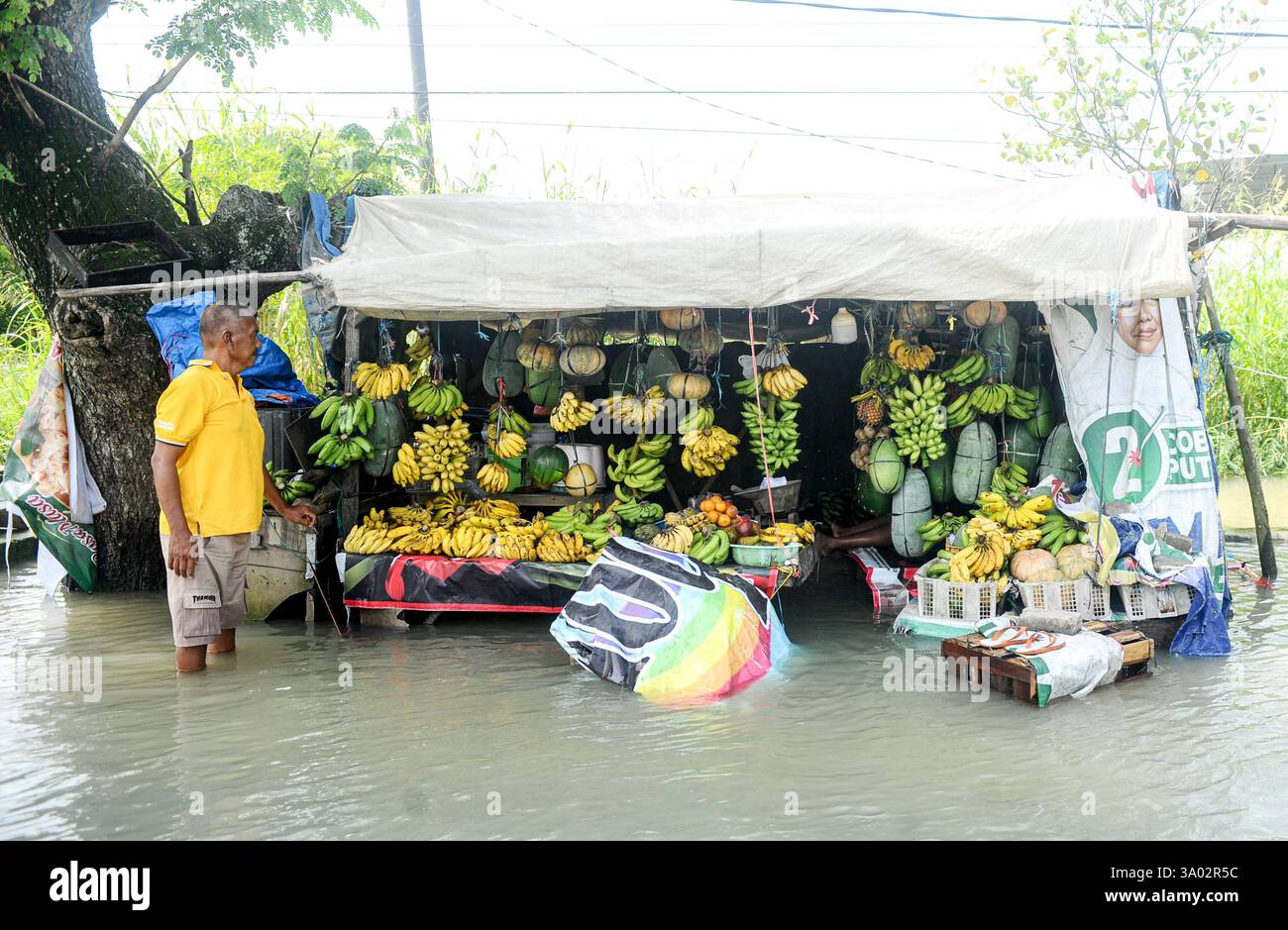 Gresik, Indonesia. 2nd Mar, 2025. A man stands near his fruits stall after heavy rain hit ...