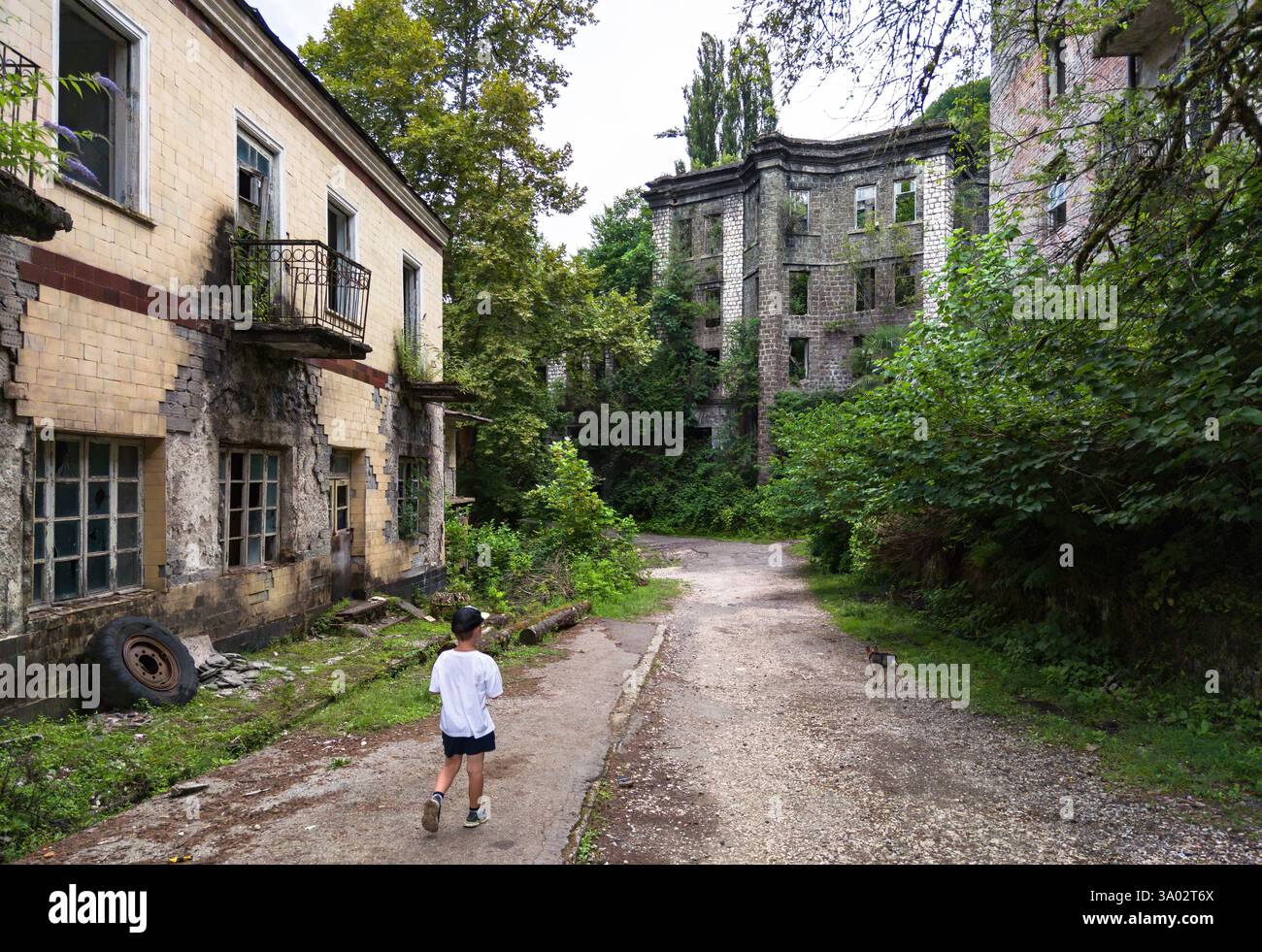 Child kid walks on abandoned ruined street in Akarmara town, Tkvarcheli ...