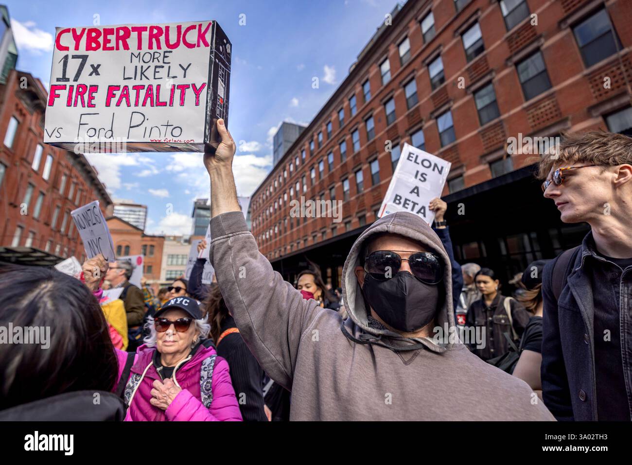 A protester holds a sign that says "Cyber truck 17x more likely fire ...