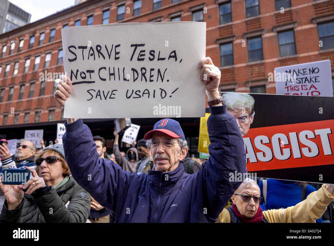 A protester holds a sign that says "Starve Tesla not children. Save ...