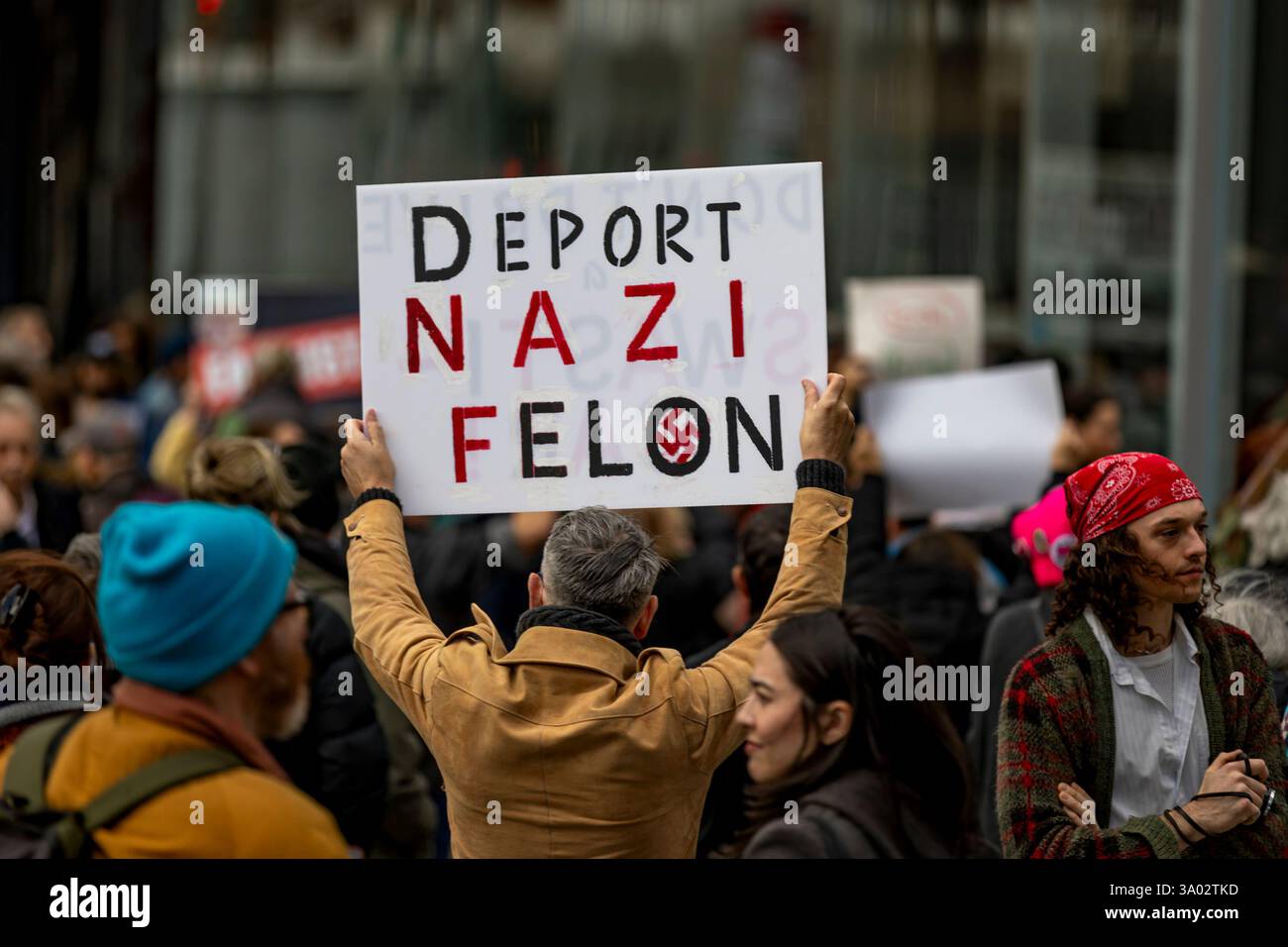 A protester holds a sign that says "Deport Nazi Felon" outside a Tesla ...