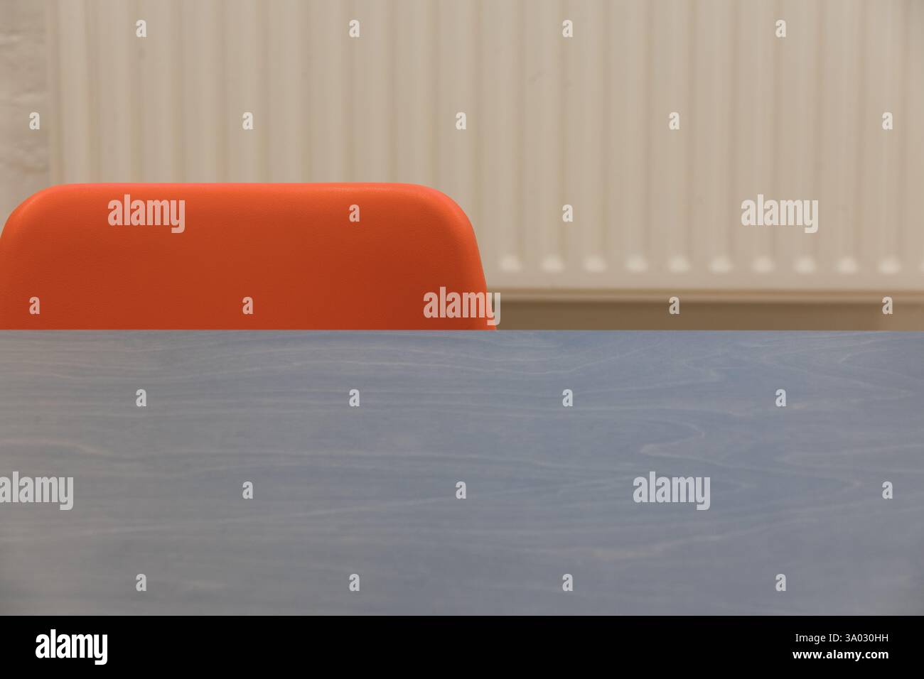Orange chair at a meeting table in a room with beige-striped walls ...