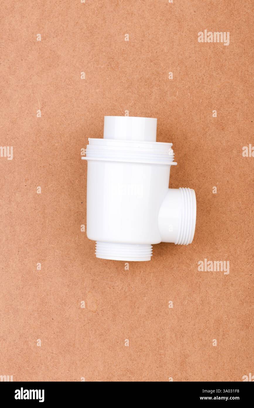 A white plastic sink drain connector with threaded ends, placed on a ...