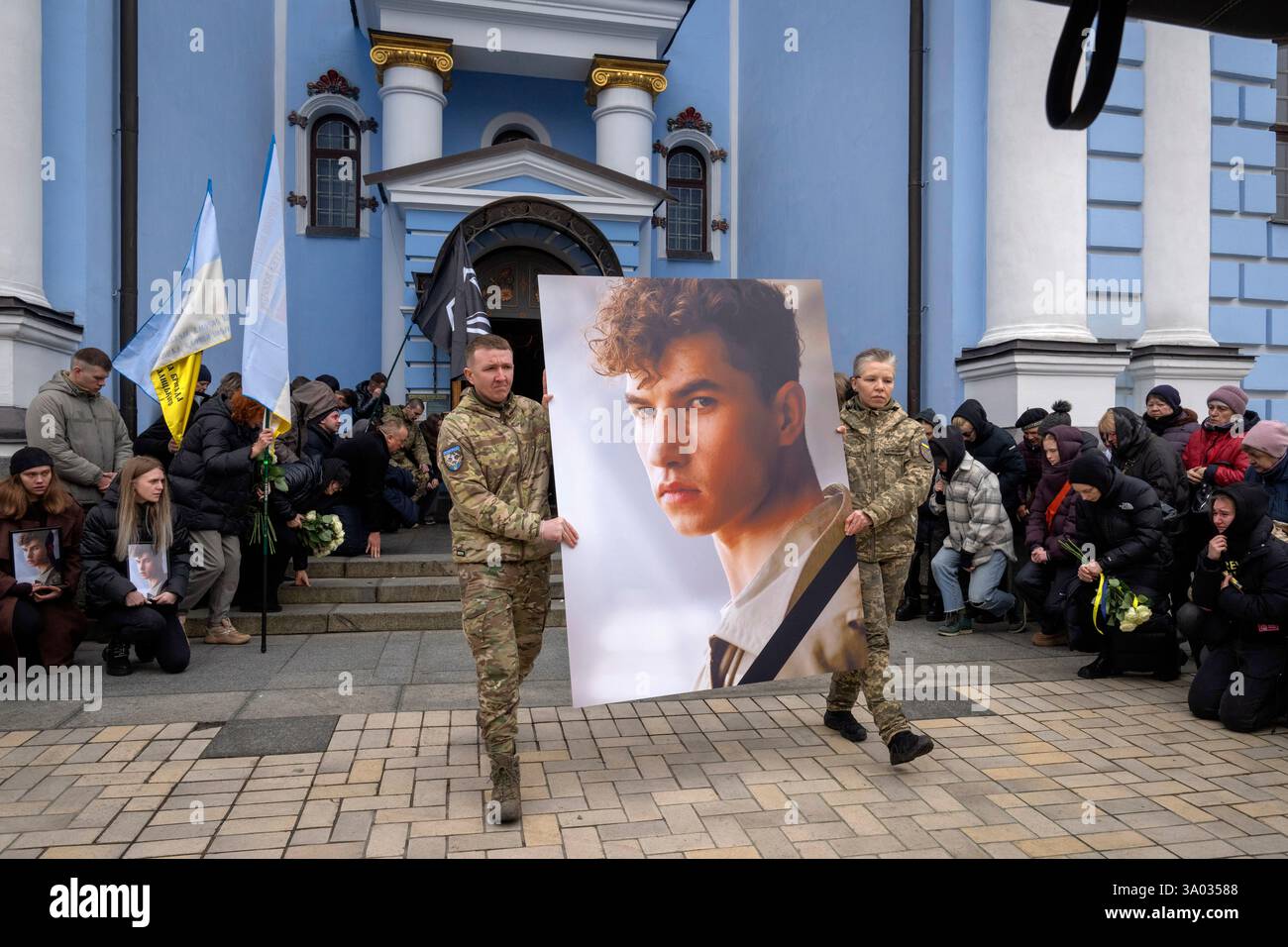 People stand kneeling as servicemen carry portrait of volunteer soldier ...