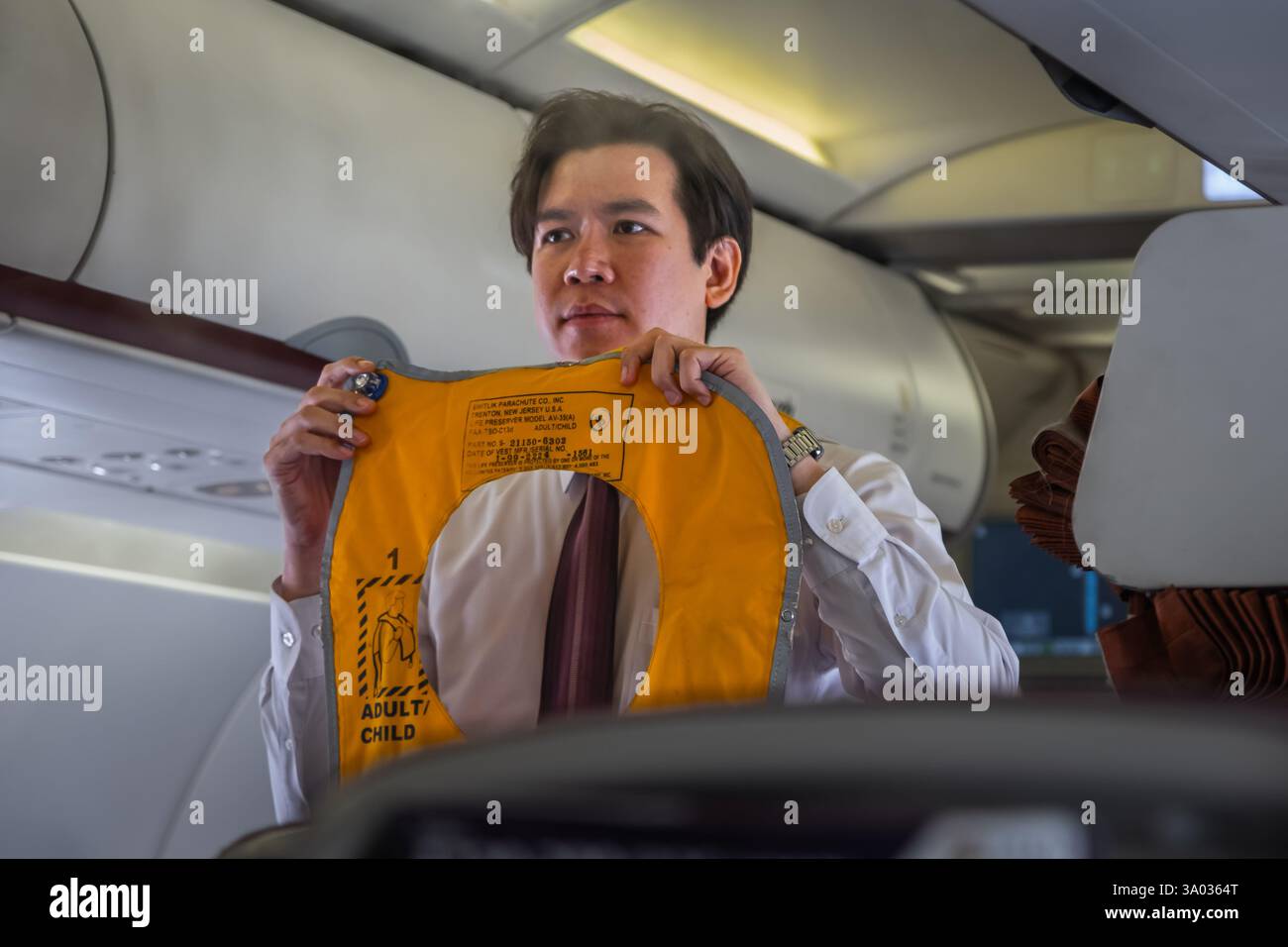 Cheerful Man flight attendant holding a life jacket and giving safety ...