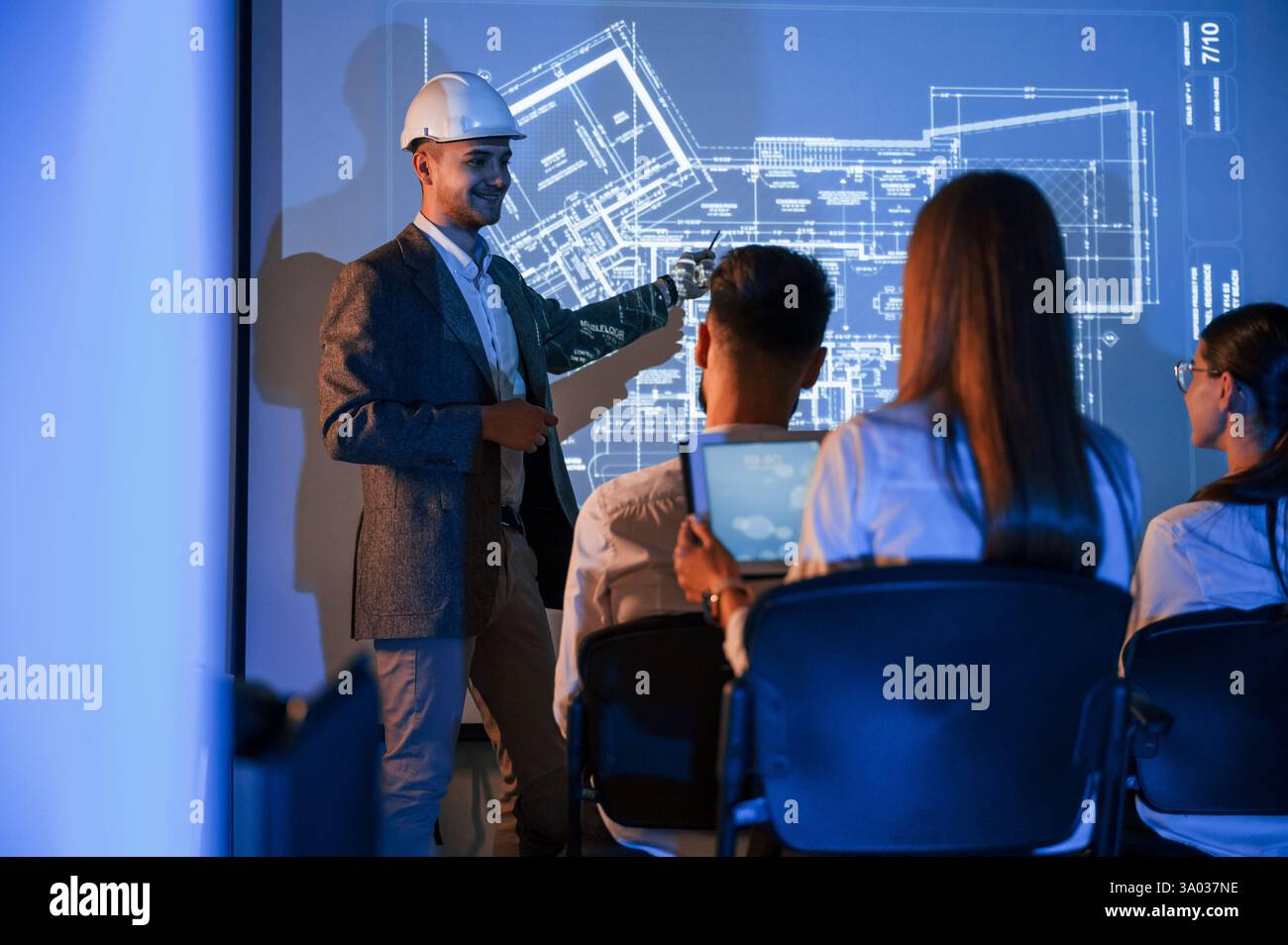 Architect showing plan of building. Male leader talking to employees ...