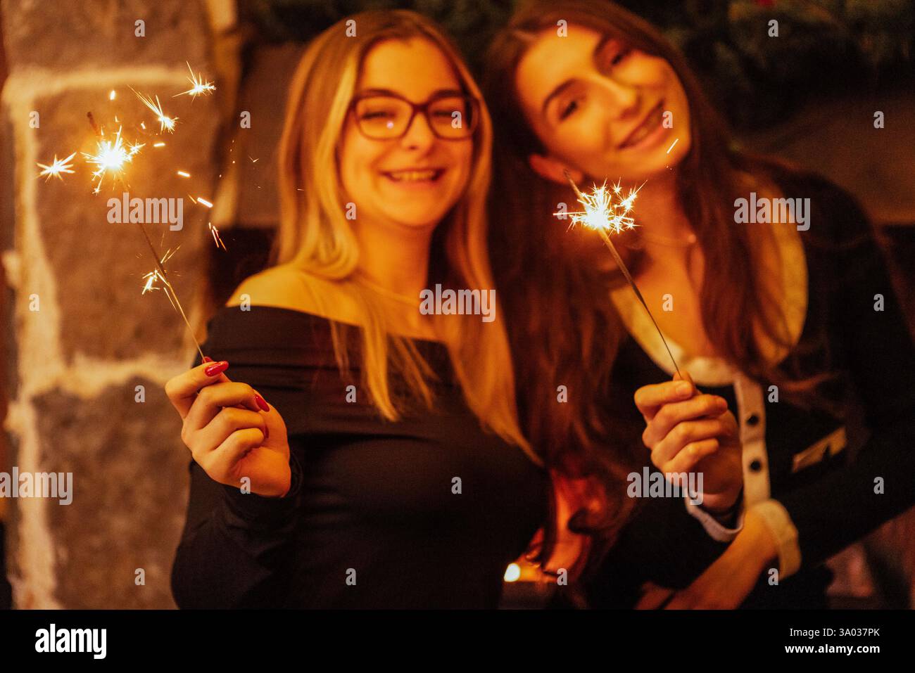 Two girls are laughing and holding sparklers. Cute smiling teenagers ...
