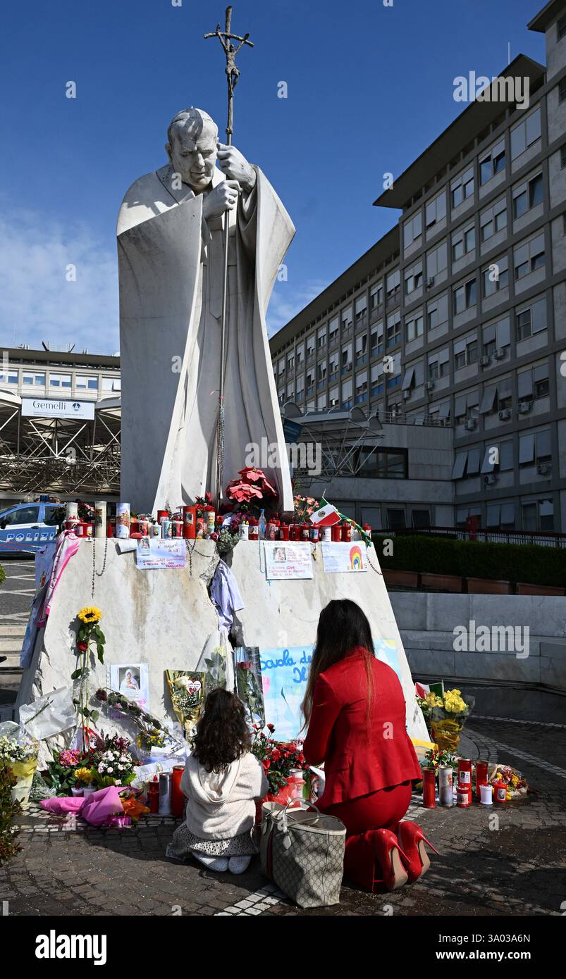People pray near the statue of John Paul II outside the Gemelli ...