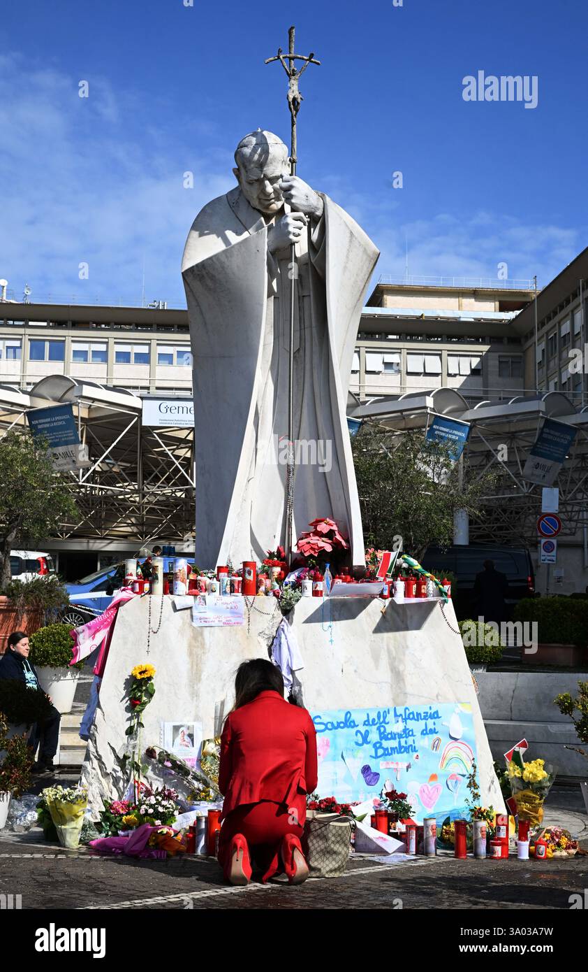 People pray near the statue of John Paul II outside the Gemelli ...