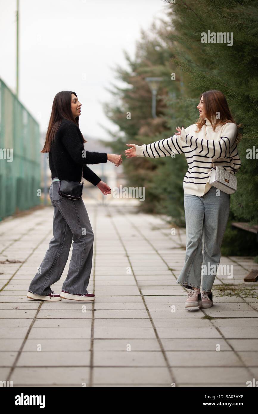 Two women smile and greet each other with outstretched arms on a ...