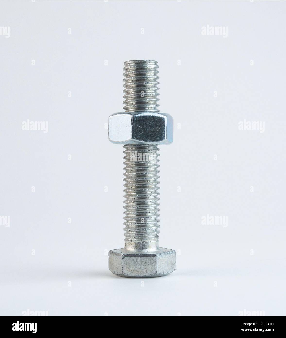 Metal bolt and nut standing upright on a plain background. High quality ...