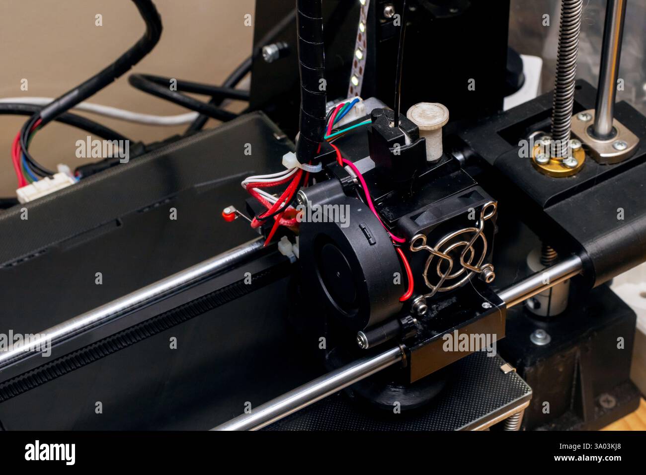 This is a detailed closeup view of a 3D printer equipped with a cooling ...