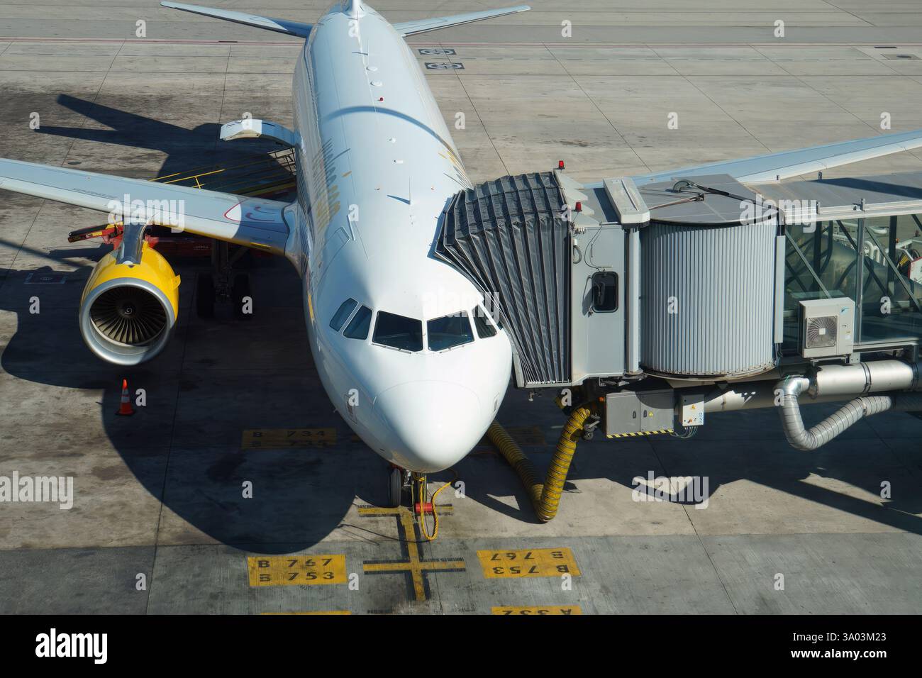 White jet plane docked at gate with passengers loading from a glass ...