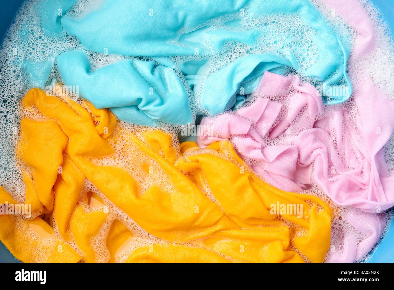 Colorful clothes soaked in water before washing, top view Stock Photo ...