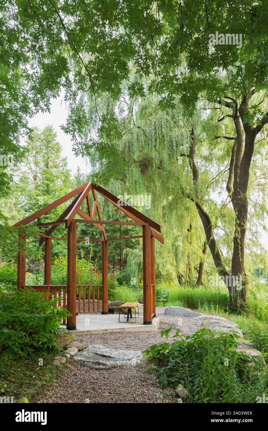 Rock edged gravel path leading to brown stained log and timber pergola ...